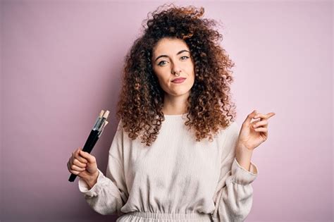 곱슬 머리와 피어싱 을 가진 젊은 아름다운 여자는 측면에 손과 손가락으로 매우 행복 한 페인트 브러쉬를 사용하여 화장품을 적용 가리키기에 대한 스톡 사진 및 기타 이미지