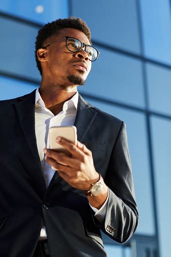 유리 건물에 서 전화를 사용하여 수염을 가진 심각한 의도적 인 젊은 아프리카 계 미국인 사업가의 아래보기 남자에 대한 스톡 사진 및 기타 이미지 Istock