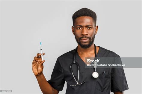 청진기를 가진 잘생긴 아프리카 의사는 회색 배경에 서 그의 손에 주사기를 보유하고 있다 의료 및 예방 접종 20 24세에 대한 스톡 사진 및 기타 이미지 Istock