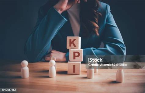 나무 블록에 Kpi 텍스트가 있는 사업가 Kpi 핵심 성과 지표 사업 목표 성과 결과 및 지표 사업 계획 및 성공 측정 목표