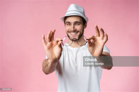 쾌활한 힙스터 남자는 행복하게 미소 핑크 스튜디오 배경을 통해 자연스럽게 고립 된 옷을 입고 흥분 한 표정을 가지고있다 사람 청소년 감정 개념 개념에 대한 스톡 사진 및