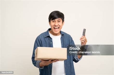 고립된 흰색 배경에 서 있는 많은 소포 판지를 가진 젊은 흥분된 아시아 남자 택배 서비스에서 택배 상자를 많이 들고 있는 쾌활한 남성 고객에 대한 스톡 사진 및 기타 이미지