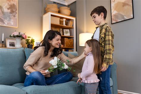 엄마에게 꽃을 주는 행복한 아이들 해피 어머니의 날 어린이 소년과 소녀는 미소 짓는 어머니를 축하하고 휴일 축하 기간 동안 장미 꽃다발과 선물 상자를줍니다 가족에 대한 스톡