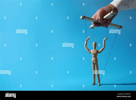 Man Pulling Strings Of Puppet On Light Blue Background Closeup Space For Text Stock Photo Alamy