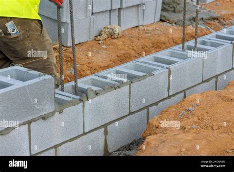 Putting Down Second Row Of Cement Blocks By Bricklayer Construction Worker In Construction Site