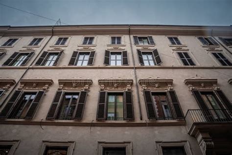 Upward View Of A Cream Stucco Apartment Facade In The Old Rome Italy With Wooden Shutters