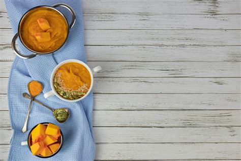 밝은 파란색 섬유 냄비 호박과 숟가락의 조각을 사용하여 흰색 나무 배경에 흰색 접시에 호박 크림 수프 평평한 평신도 복사 공간 0명에 대한 스톡 사진 및 기타 이미지