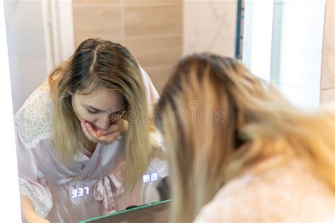 Young Girl In Front Of The Mirror Spits In Her Hand Mouthwash While