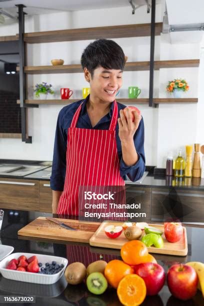 젊은 아시아 남자 와 앞치마 물고 빨간 사과 과 Fuits 에 검정 나무 테이블 건강한 생활방식에 대한 스톡 사진 및 기타 이미지 건강한 생활방식 건강한 식생활 과일