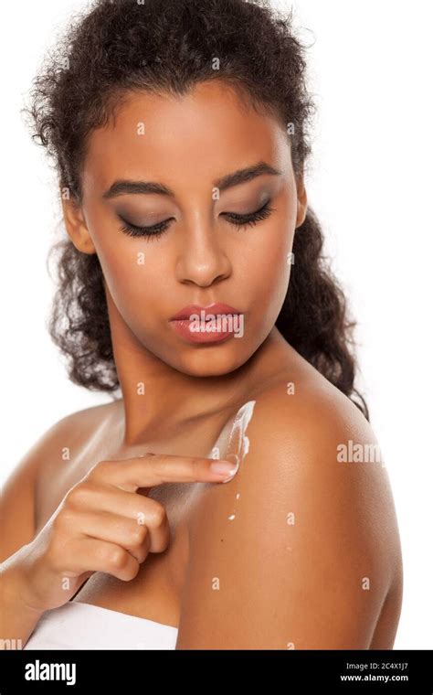 Beautiful Dark Skinned Woman Applying Body Lotion On White Background