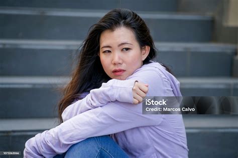 젊은 슬 프 고 우울 아시아계 미국인 학생 여자 또는 야외에서 압도 하 고 절망적 인 기분이 불안 거리 계단에 앉아 왕 따 십 대 고통 우울증 문제 거리에 대한 스톡 사진