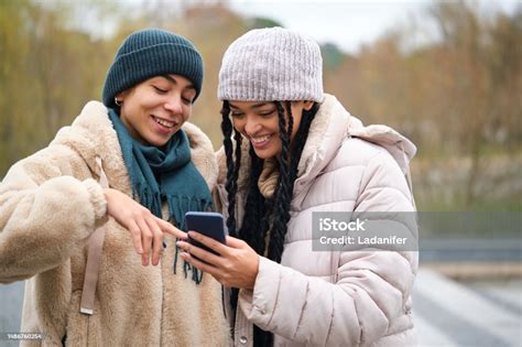 겨울에 거리에서 전화를 사용하는 행복한 도미니카 레즈비언 커플 20 29세에 대한 스톡 사진 및 기타 이미지 20 29세