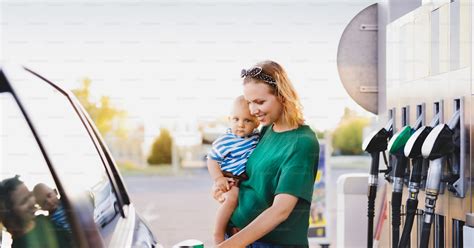 주유소에서 아기를 데리고 차에 연료를 보급하는 젊은 어머니 사진 Unsplash의 산업 이미지