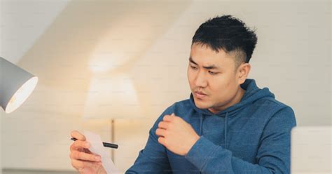 아름 다운 젊은 웃는 아시아 남자는 집에서 거실에서 책상에서 노트북을 작업 하 고 있습니다 홈 오피스에서 노트북 문서 금융 및 계산기를 쓰는 아시아 사업가 집에서 시간을