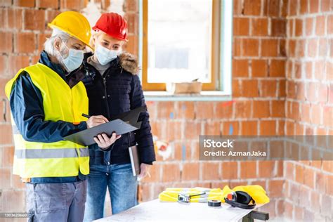 남성 계약 건설 노동자와 여성 클라이언트 하드 모자와 얼굴 마스크에 새로운 건물의 개발을 논의 50 54세에 대한 스톡 사진 및 기타 이미지 Istock