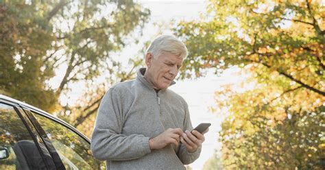 차 근처에 서서 숲에서 산책을 준비하는 동안 스마트폰에서 무언가를 검색하는 백인 노인의 낮은 각도 보기 사진 Unsplash의 문자 메시지 이미지