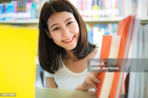 대학의 현대 인테리어 도서관에서 책장 근처 수업 사이의 휴식 동안 명랑 한 여성 아시아 학생 소녀 독서 책 교육 지혜와 연구 개념 20 29세에 대한 스톡 사진 및 기타