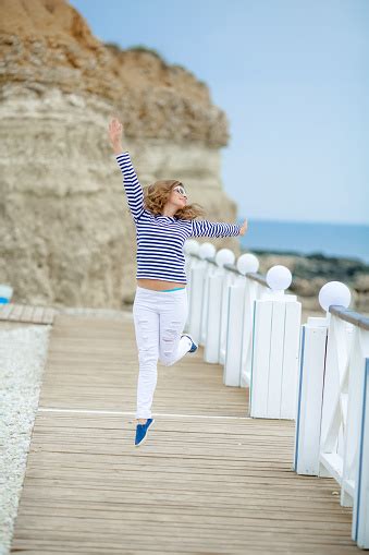 매력적인 예쁜 젊은 힙 스 터 여 자가 여름에는 세련 된 청바지에 있는 운동 화에 흰색 T 셔츠는 도시의 나무 벽 근처에 서 있다 화창한 여름날에 걷는 유럽 소녀 T 셔츠에