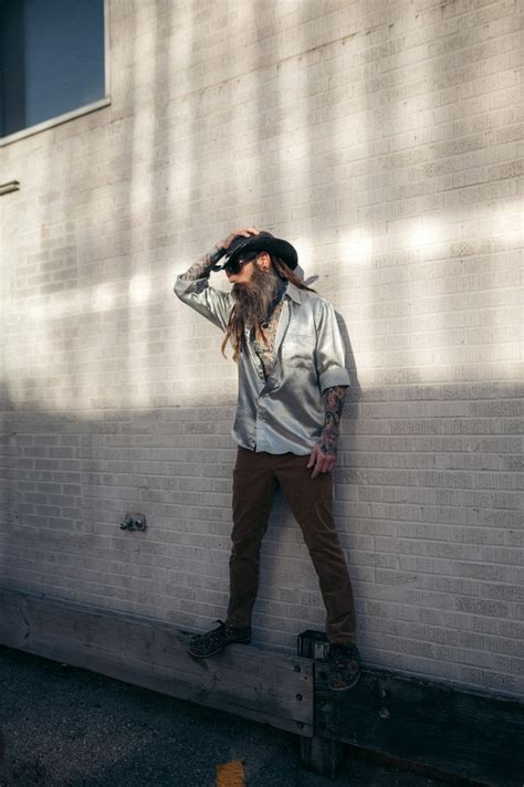 긴 머리와 벽에 기대어 있는 수염을 가진 남자 사진 Unsplash의 무료 의류 이미지