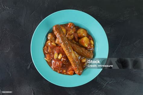 감자 당근 콩을 곁들인 수제 소시지 캐서롤 이미지에 풍미있는 토마토 그레이비 슬레이트 배경의 청록색 파란색 접시에 스튜 전경에 초점을 맞추고 0명에 대한 스톡 사진 및 기타