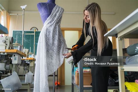 테일러는 마네킹 위에 천을 드리우고 가위를 사용하여 낮 동안 밝은 바느질 스튜디오에서 정확한 디자인을 만듭니다 25 29세에 대한 스톡 사진 및 기타 이미지 Istock