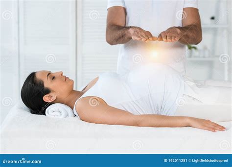 View Of Man Healing Attractive Pregnant Woman Lying On Massage Table