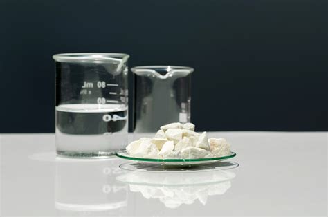 화학 시계 유리의 탄산 칼슘 칩은 비커의 맑은 액체 옆에 배치됩니다 흰색 실험실 테이블에 화학 성분을 클로즈업 사이드 뷰 백악에 대한 스톡 사진 및 기타 이미지 Istock