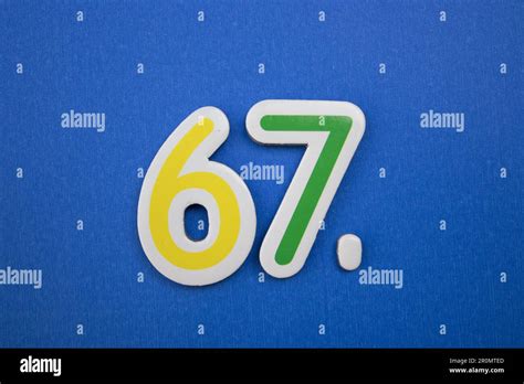 The Number 67 Placed On A Blue Background Photographed From Above Colored Yellow And Green
