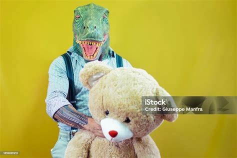 테디 베어와 T 렉스 공룡 마스크를 착용 하는 선임 남자 카니발과 발렌틴 데이를 축하하는 재미를 가진 미친 사람 터무니없고 초현실적 인 재미있는 개념 노란색 배경 이미지