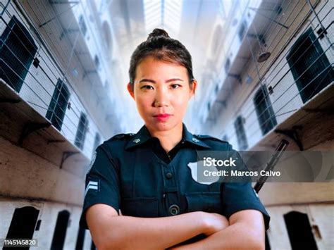 범죄 처벌과 법 집행 개념에서 경찰 유니폼을 입고 국가 교도소 감옥에 서 서 젊은 심각 하 고 매력적인 아시아 중국 가드 여자의 초상화 경찰관에 대한 스톡 사진 및 기타