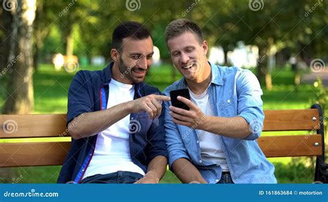 Os Melhores Amigos Do Sexo Masculino A Ver Fotografias No Smartphone A Divertir Se No Parque