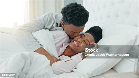 사랑하고 자고 아침에 침대에서 흑인 커플과 키스를 나누며 집에서 함께 휴식을 취합니다 침실에서 남자와 여자가 휴일에 행복해 보이는 미소 환대 또는 휴가 행복에 대한 스톡