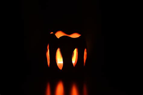 불이 켜진 촛불은 검은 배경에 촛대 내부에 타오른다 자신의 손으로 점토로 만든 촛불 홀드의 슬릿에서 아름다운 화재 빛 촛불의 눈부심이 반영됩니다 0명에 대한 스톡 사진 및