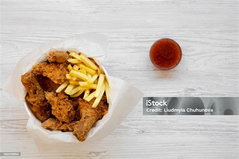 맛 있는 패스트 푸드 프라이드 치킨 나지만 매운 날개 감자 튀김 및 닭 손가락 종이 상자에 있는 흰색 배경에 나무 오버 헤드