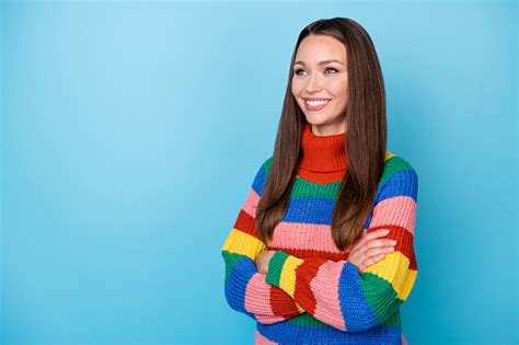 긍정적 인 쾌활한 소녀 노동자 룩 카피 스페이스 크로스 핸즈의 설정 사진은 블루 컬러 배경을 통해 고립 된 무지개 스타일 풀오버를 선택 선택 선택합니다 갈색 머리에 대한