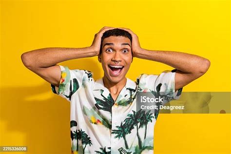 코를 뚫고 옷을 입고 인쇄 셔츠를 입고 머리에 팔을 가진 인상 깊은 펑키 남자의 사진 놀란 노란 색 배경에 고립 된 응시 Omg