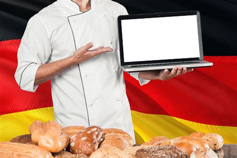 독일 국기와 빵 배경에 노트북을 들고 독일 베이커 요리사가 복사 공간에 대 한 균일 한 포인팅 빈 화면을 착용 고급 요리에 대한 스톡 사진 및 기타 이미지 Istock