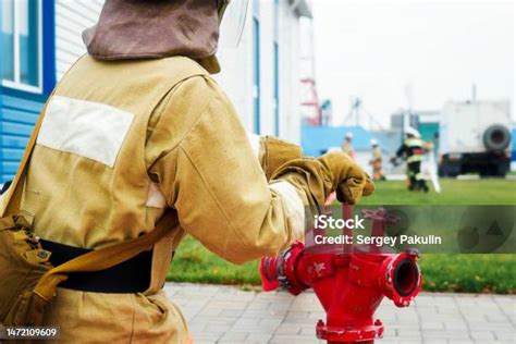 헬멧과 보호 복을 입은 소방 구조대원은 거리의 소화전 옆에 앉아 있습니다 뒤에서 본 모습 소화 준비 관 튜브에 대한 스톡 사진 및 기타 이미지 Istock