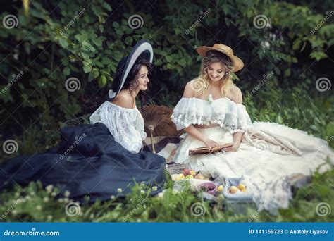 Two Beautiful Girls Are Reading A Book In Nature Stock Image Image Of