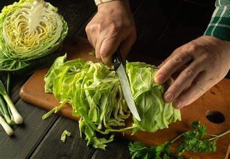 Premium Photo Cutting Fresh Cabbage With A Knife In The Hands Of A