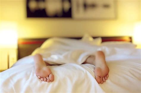 A Person Laying On A Bed With Their Feet Up Sleeping Tired Bed
