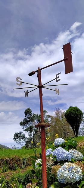 약간 녹슨 붉은 색의 날씨 베인 또는 푸른 하늘을 향한 바람 베인이 Munnar 꼭대기 역에서 바람의 방향을 알려줍니다 도로에