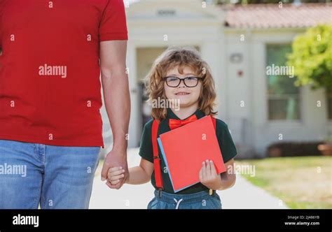 Portrait Of Happy Nerd Pupil Holding Teachers Hand Father And Son Walking Trough School Park
