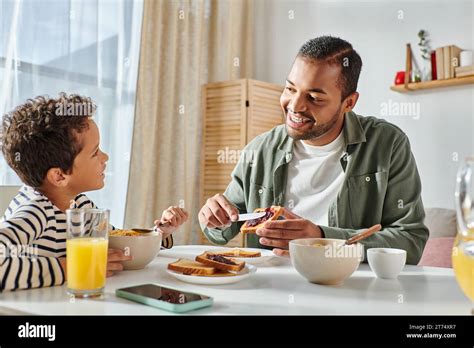 Good Looking African American Father Spreading Jam On Toast And Smiling