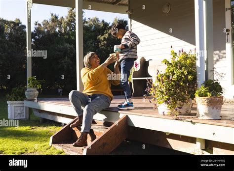 Happy Biracial Grandmother And Grandson Drinking Tea Sitting In Garden Stock Photo Alamy
