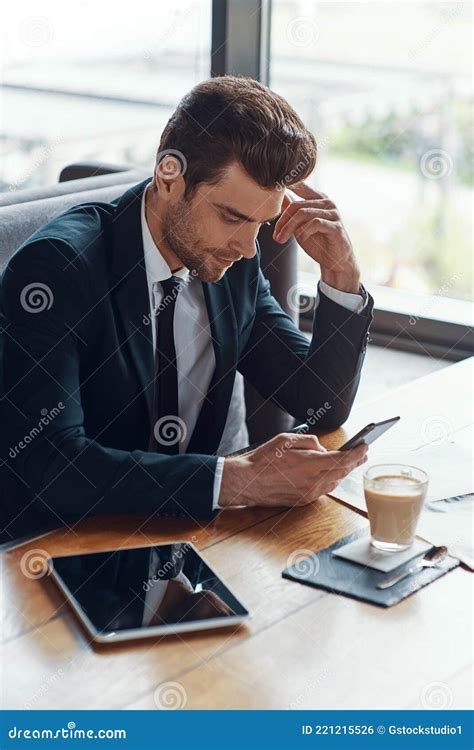 занятой молодой бизнесмен в полном костюме с помощью смартфона сидя в ресторане Стоковое Фото