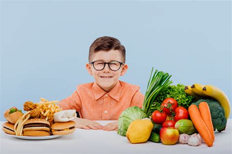 패스트 푸드 안경을 쓰고 미소 짓고 있는 어린 소년 건강한 음식과 건강에 해로운 음식 푸른 배경에 고립 스튜디오 테이블에서 복사 공간 고기에 대한 스톡 사진 및 기타 이미지