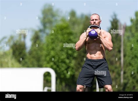 Man Exercising With Kettle Bell Outdoor And Flexing Muscles Muscular