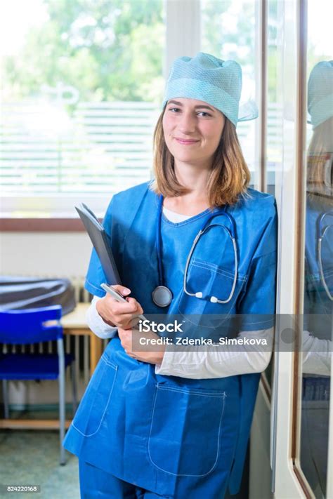파란색 유니폼 병원 컨설팅 룸에 서 서 카메라를 보며 웃 고 있는 젊은 여성 의학 박사 여자는 폴더와 펜 청진 기는 그녀의 목 건강 진단에 대한 스톡 사진 및 기타 이미지