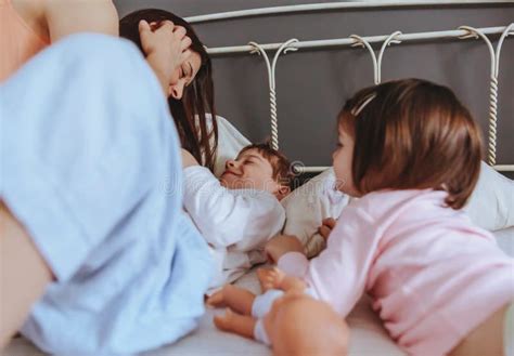 Madre Relajada E Hijos Que Juegan Sobre La Cama Foto De Archivo